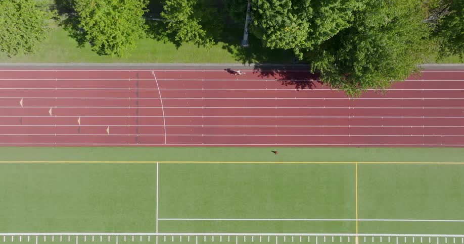 Oval Running Track A Lone Athlete Runs In The Outer Lane Of An Outdoor